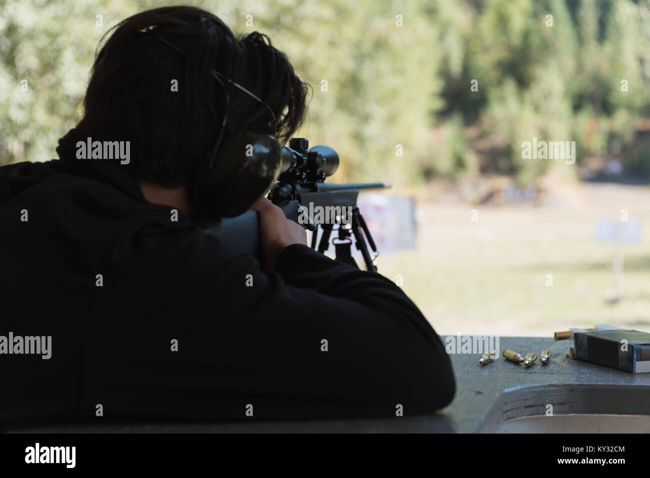 Man aiming sniper rifle at target in shooting range Stock Photo - Alamy