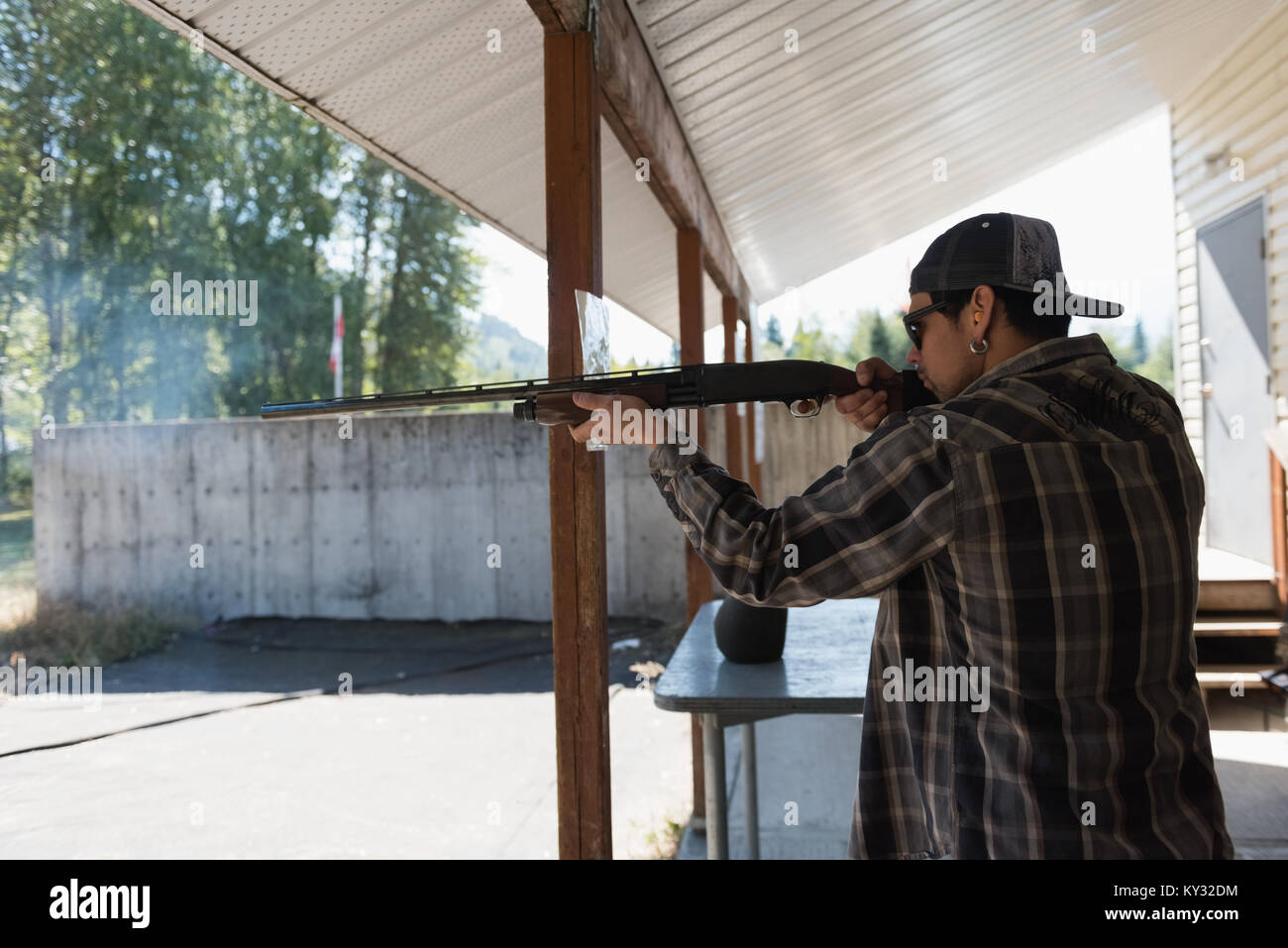 Man aiming shotgun at target in shooting range Stock Photo - Alamy