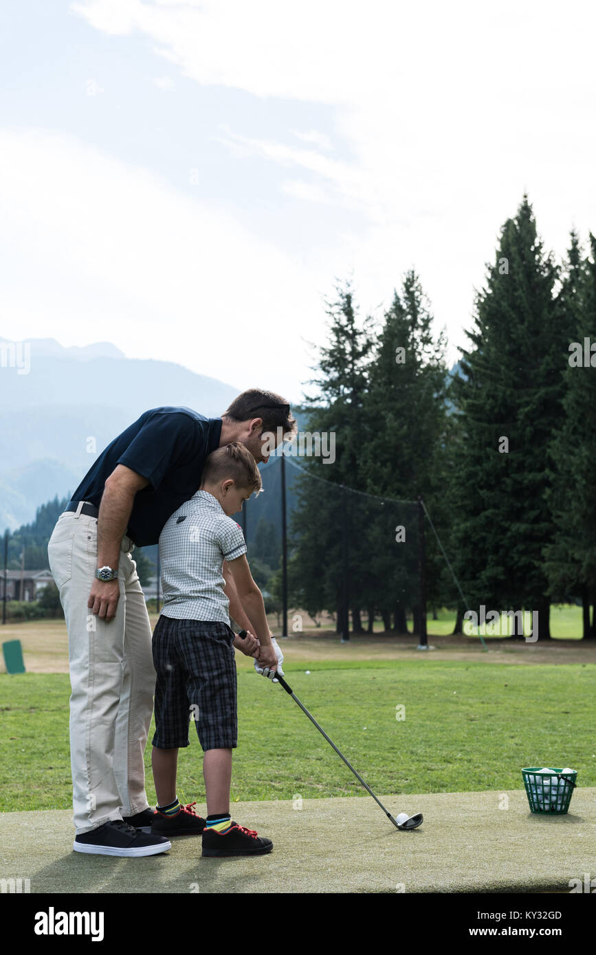 Father assisting his son to play golf Stock Photo - Alamy