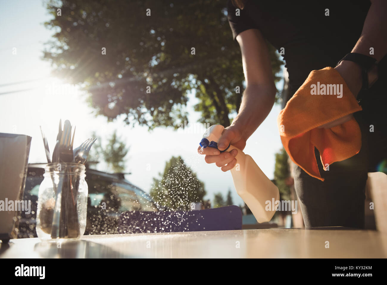 Worker spraying water while cleaning table Stock Photo - Alamy