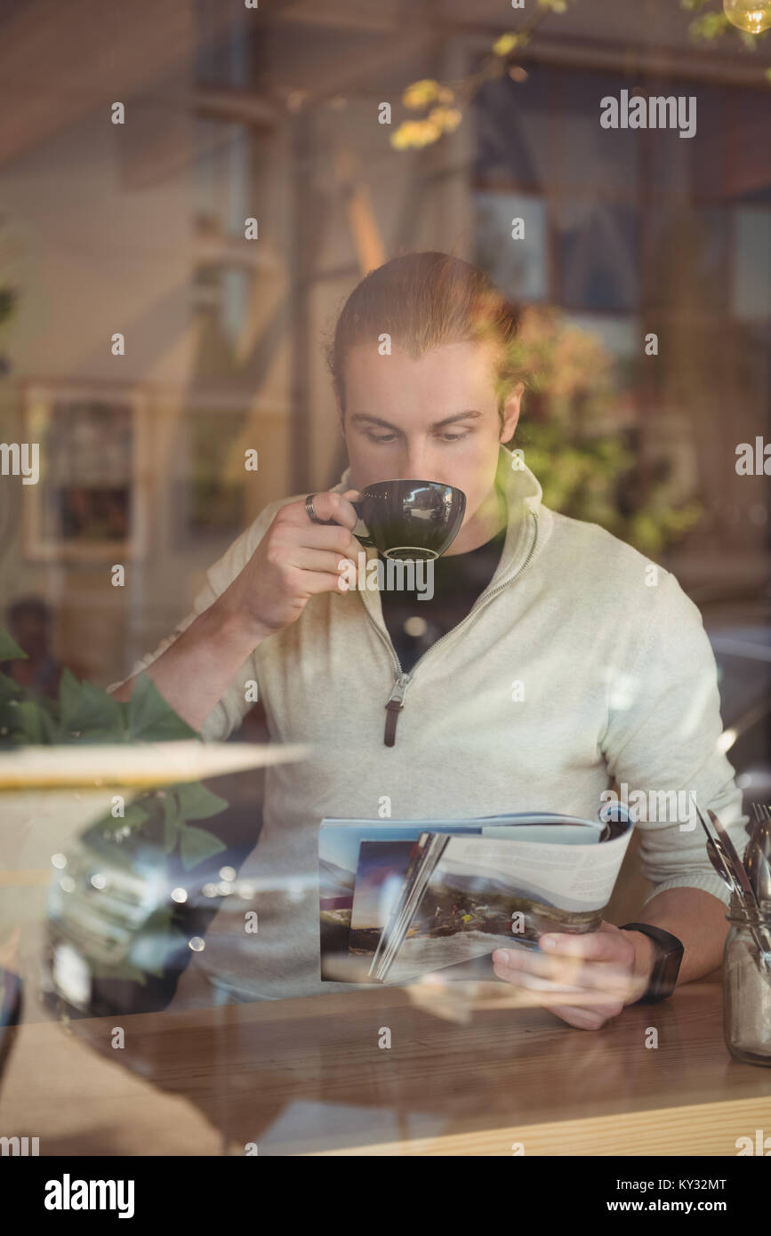 Man having coffee while reading magazine Stock Photo - Alamy