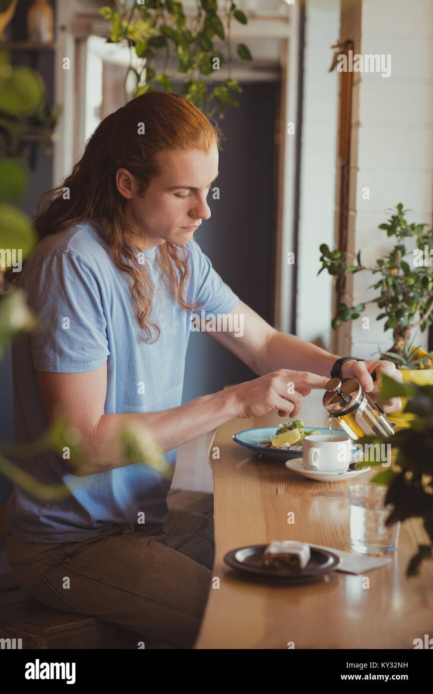 Man pouring coffee in cup at table Stock Photo - Alamy