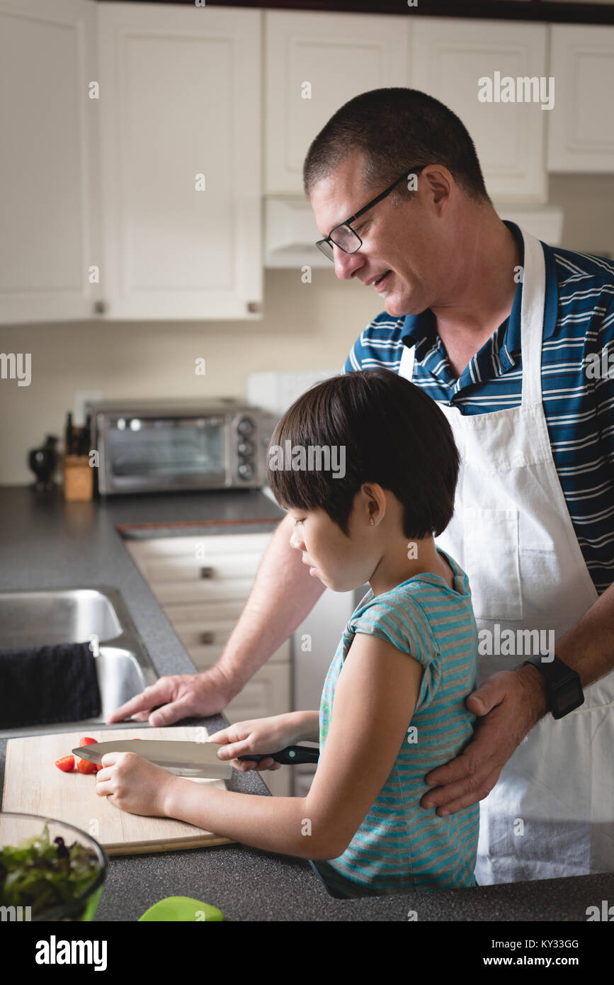 Attentive father helping his son to cut vegetables Stock Photo - Alamy
