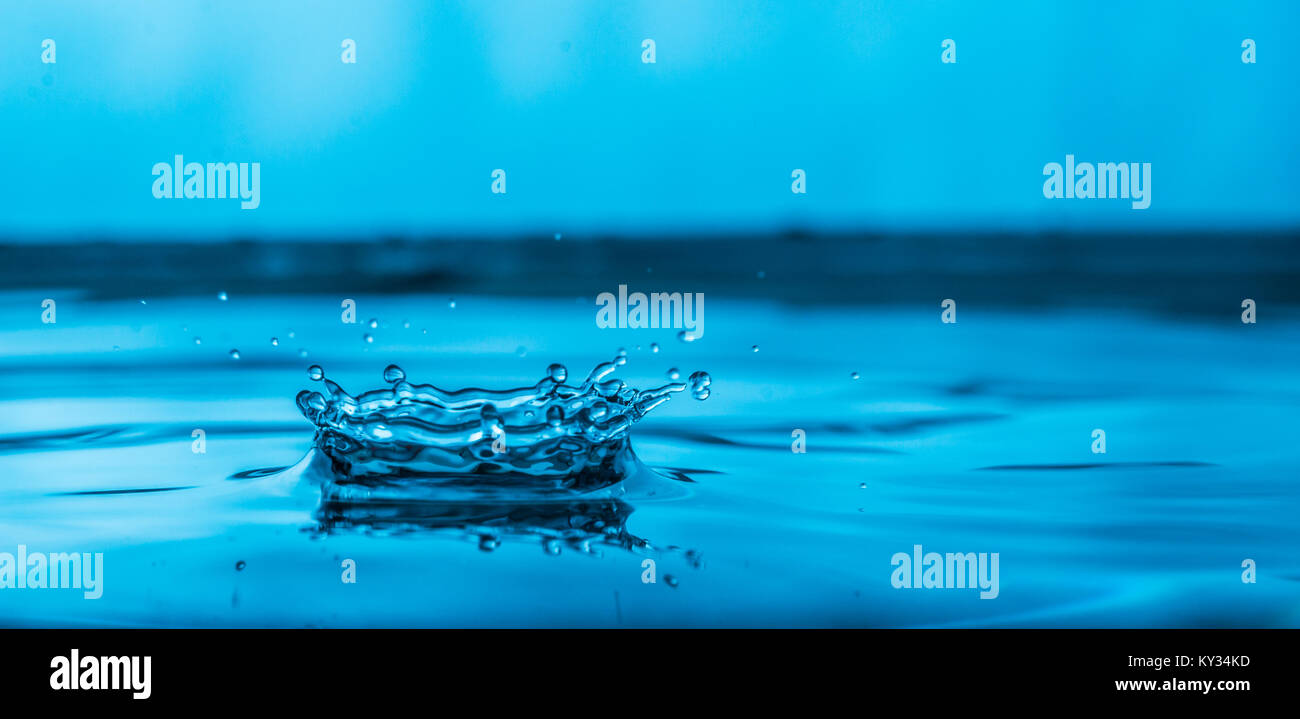 water drop splash in a glass blue colored Stock Photo - Alamy