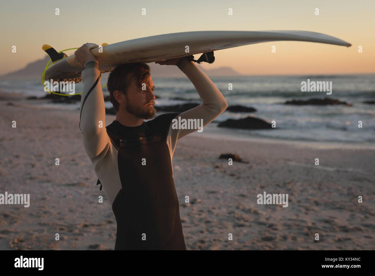 Surfer carrying surfboard on head Stock Photo - Alamy