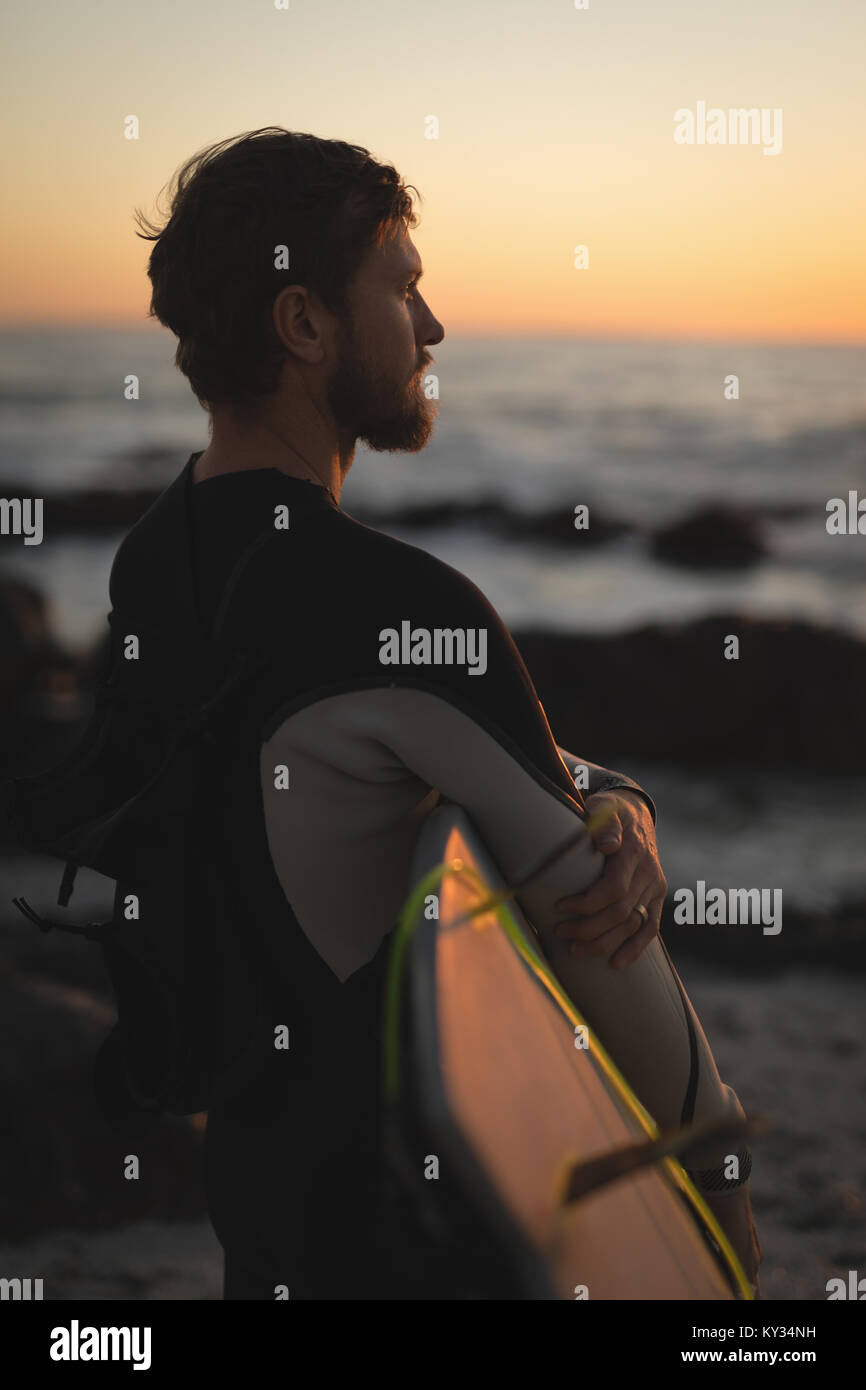 Surfer with surfboard standing on beach Stock Photo - Alamy