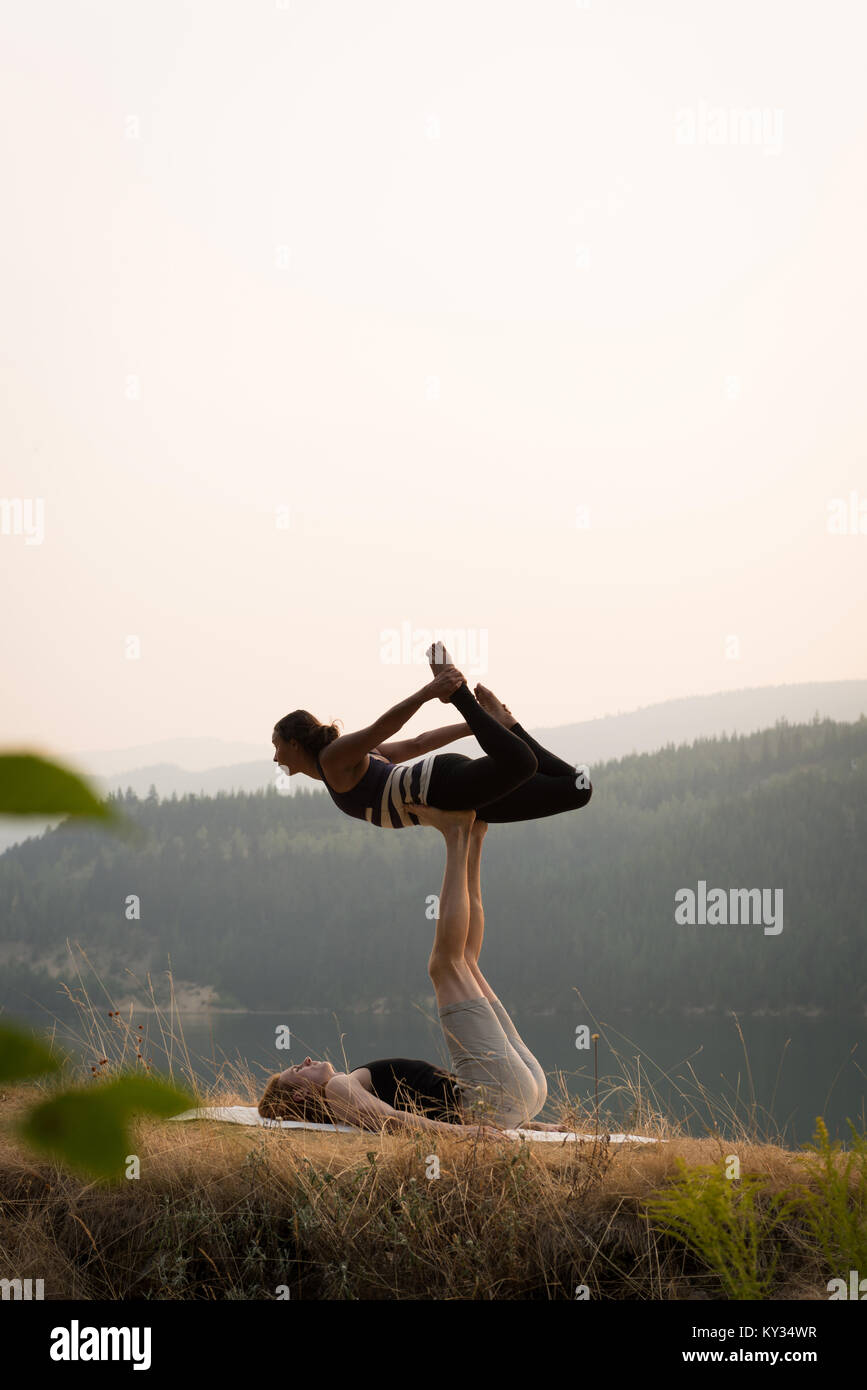 Sporty couple practicing acro yoga in a lush green ground Stock Photo ...