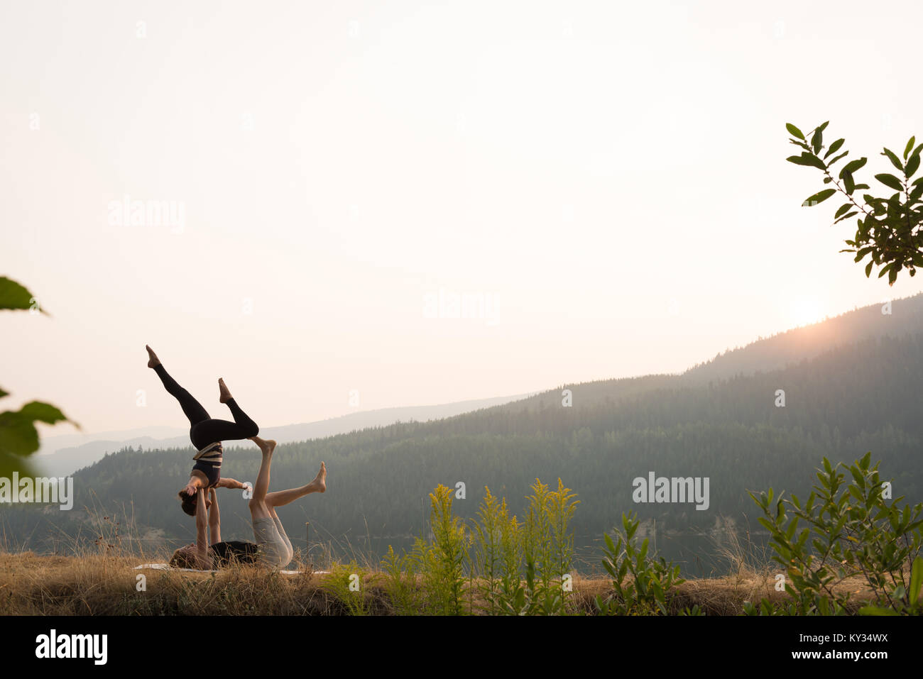 Sporty couple practicing acro yoga in a lush green ground Stock Photo ...