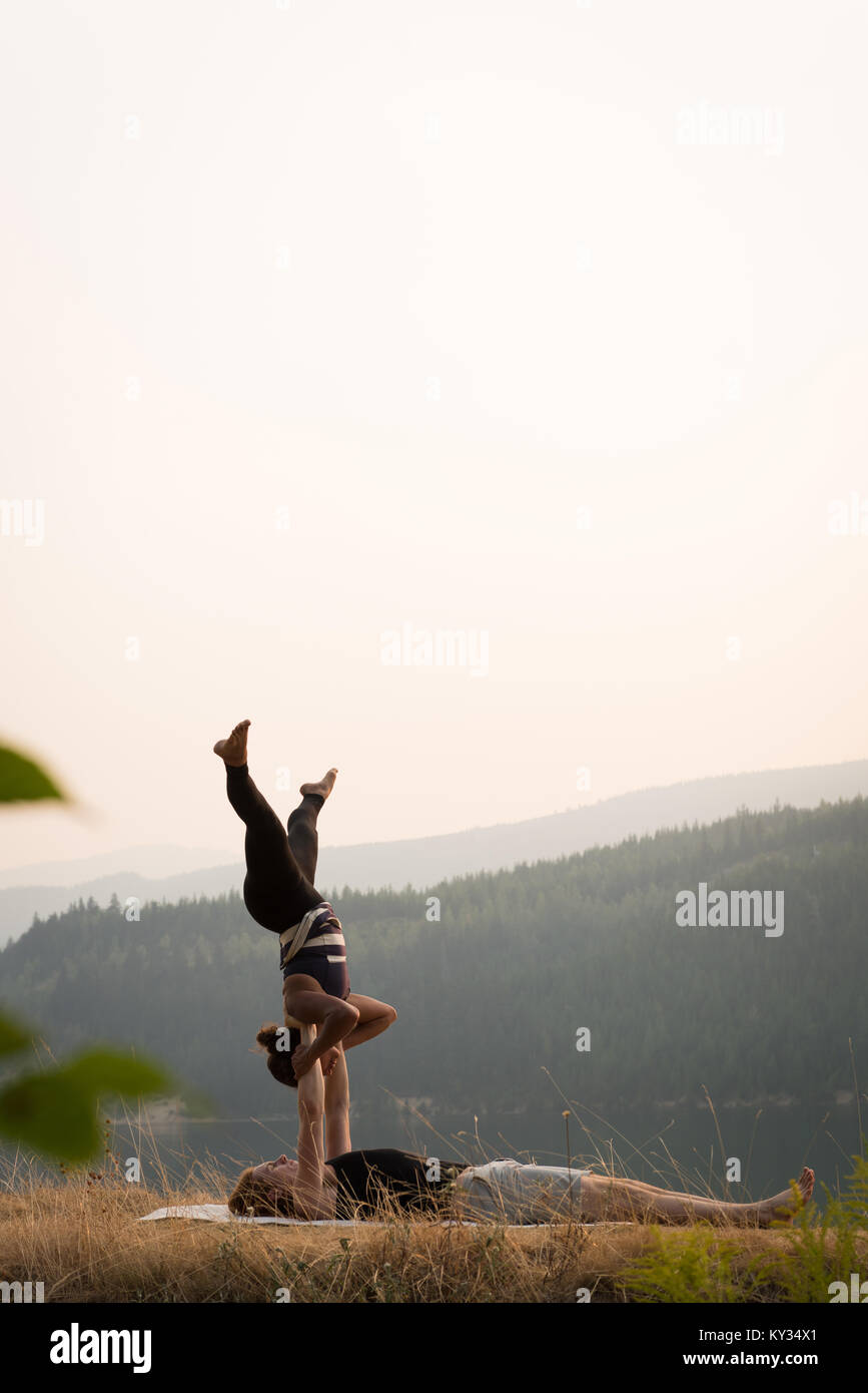 Sporty couple practicing acro yoga in a lush green ground Stock Photo ...