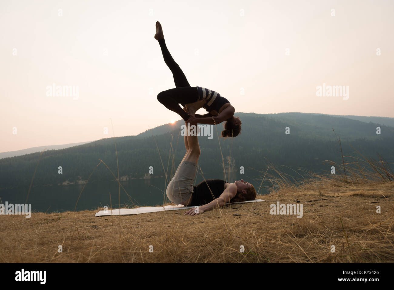 Sporty couple practicing acro yoga in a lush green ground Stock Photo ...