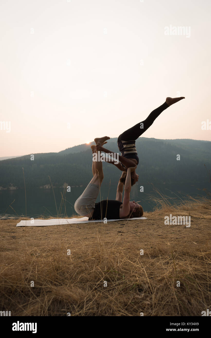 Fit couple practicing acro yoga in a lush green ground Stock Photo - Alamy