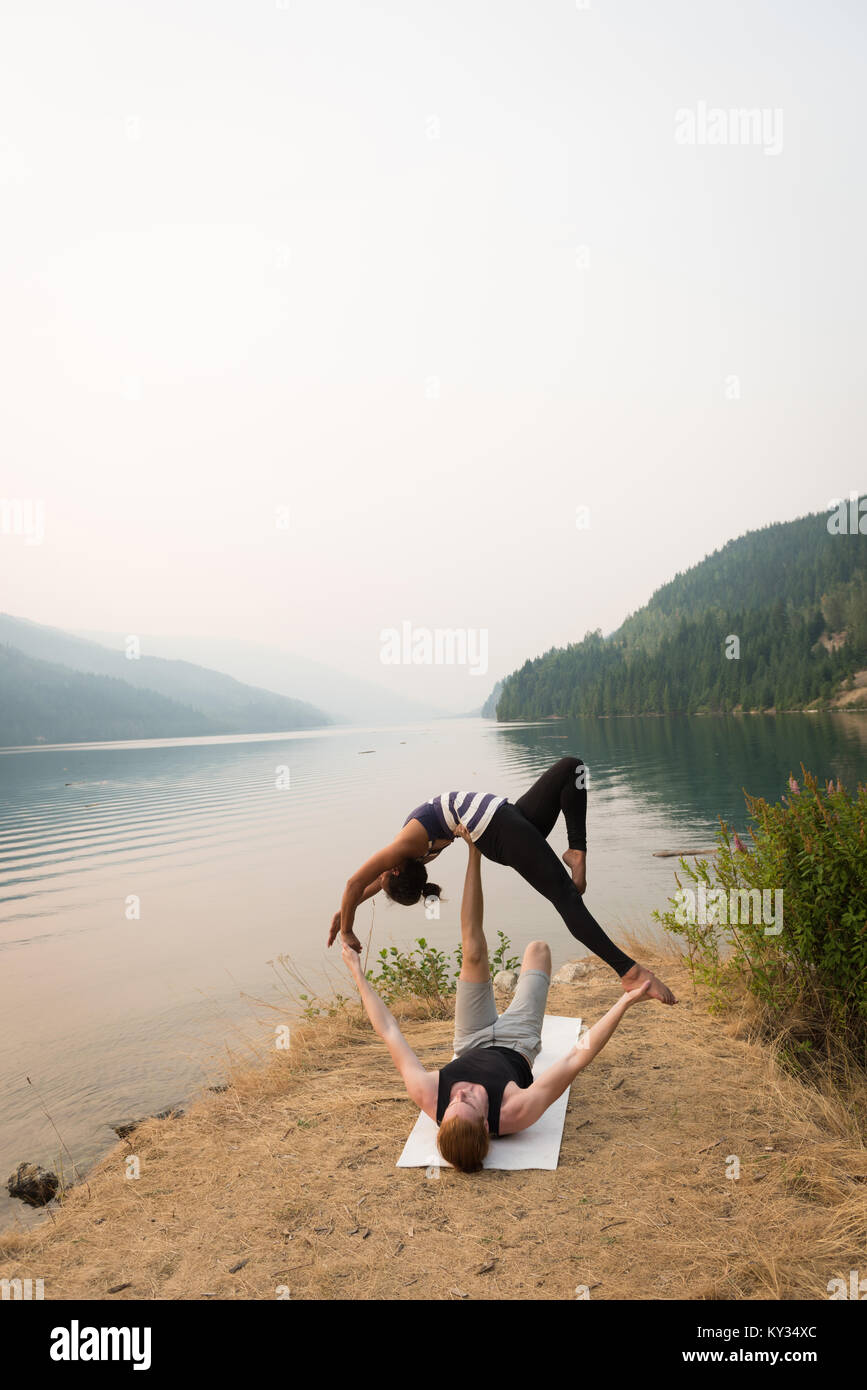 Fit couple practicing acro yoga in a lush green ground Stock Photo - Alamy