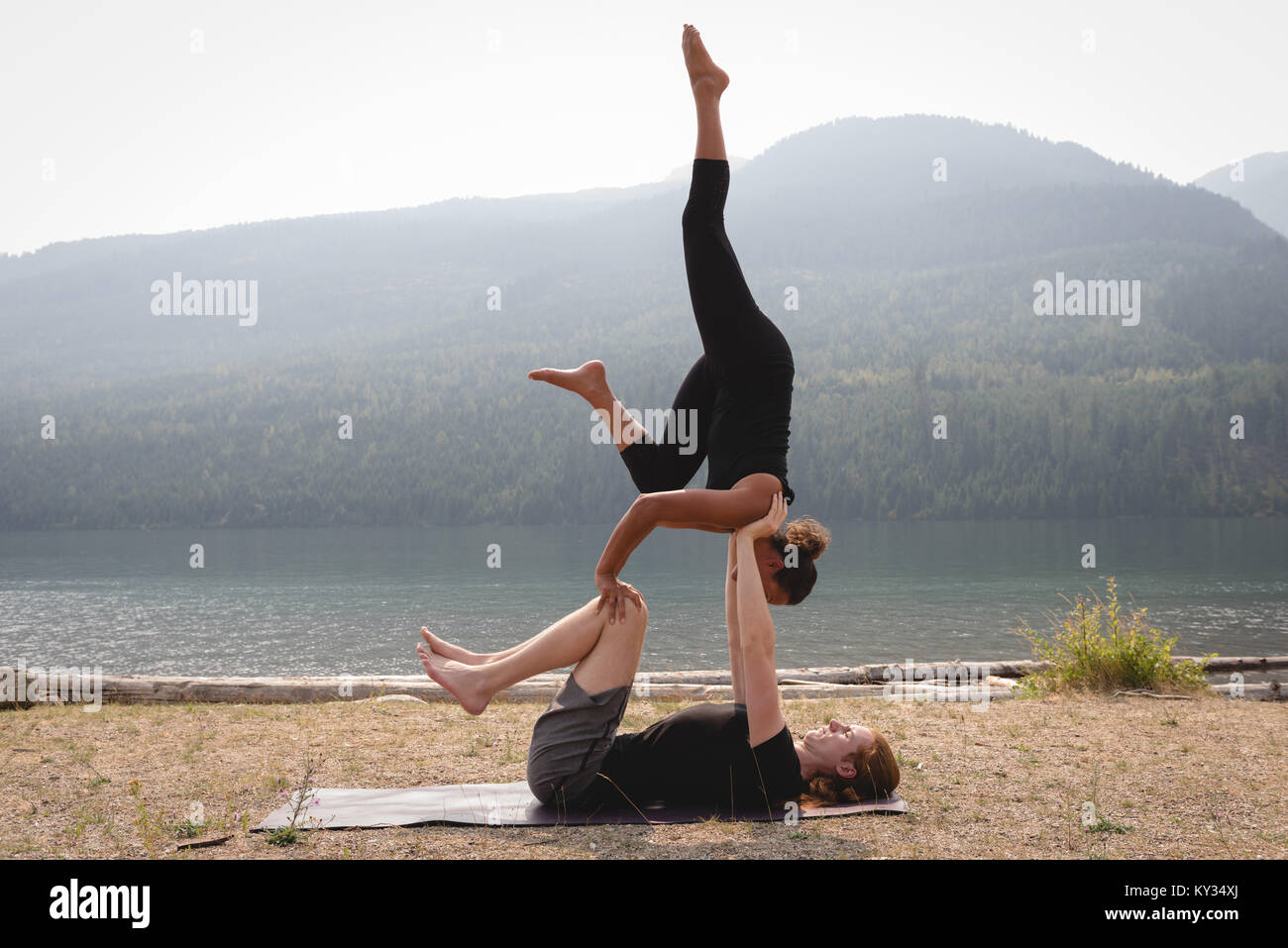 Fit couple practicing acro yoga in a lush green ground Stock Photo - Alamy