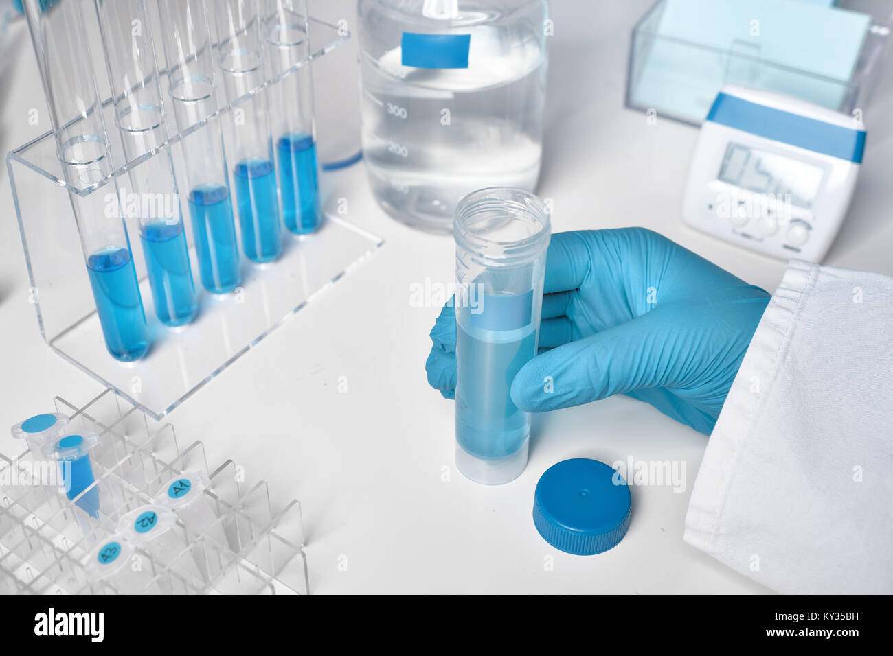 Scientific background in white and blue. Liquid sample in gloved female ...