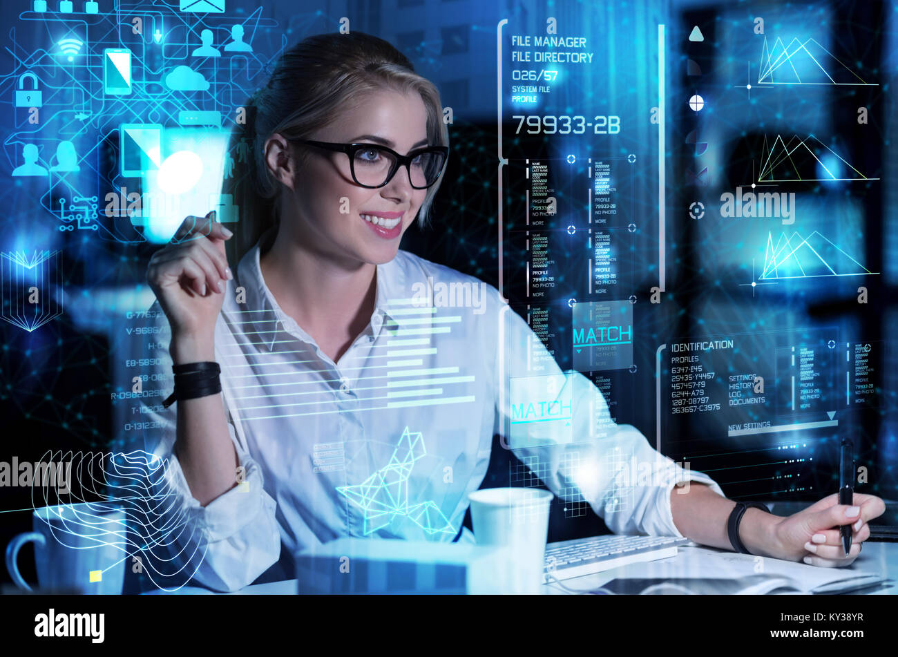 Young programmer smiling while looking at the screen and making notes ...