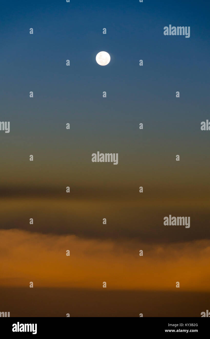 Full moon over clouds at sunset, from aeroplane flying over Tasman Sea ...