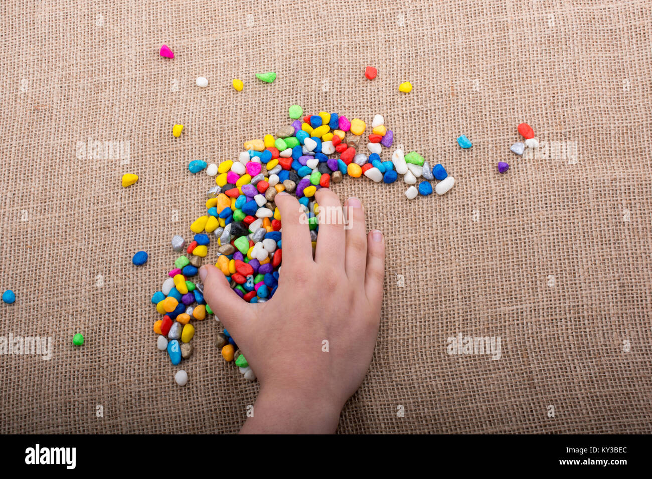 Colorful little pebbles in hand and on canvas ground Stock Photo - Alamy