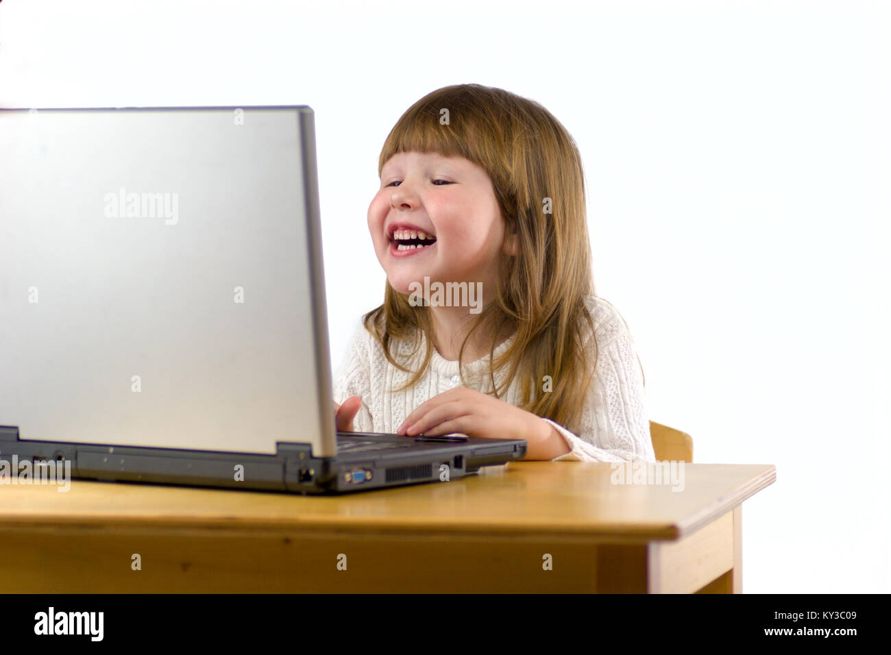 Little cheerful girl typing message on laptop isolated on white Stock ...