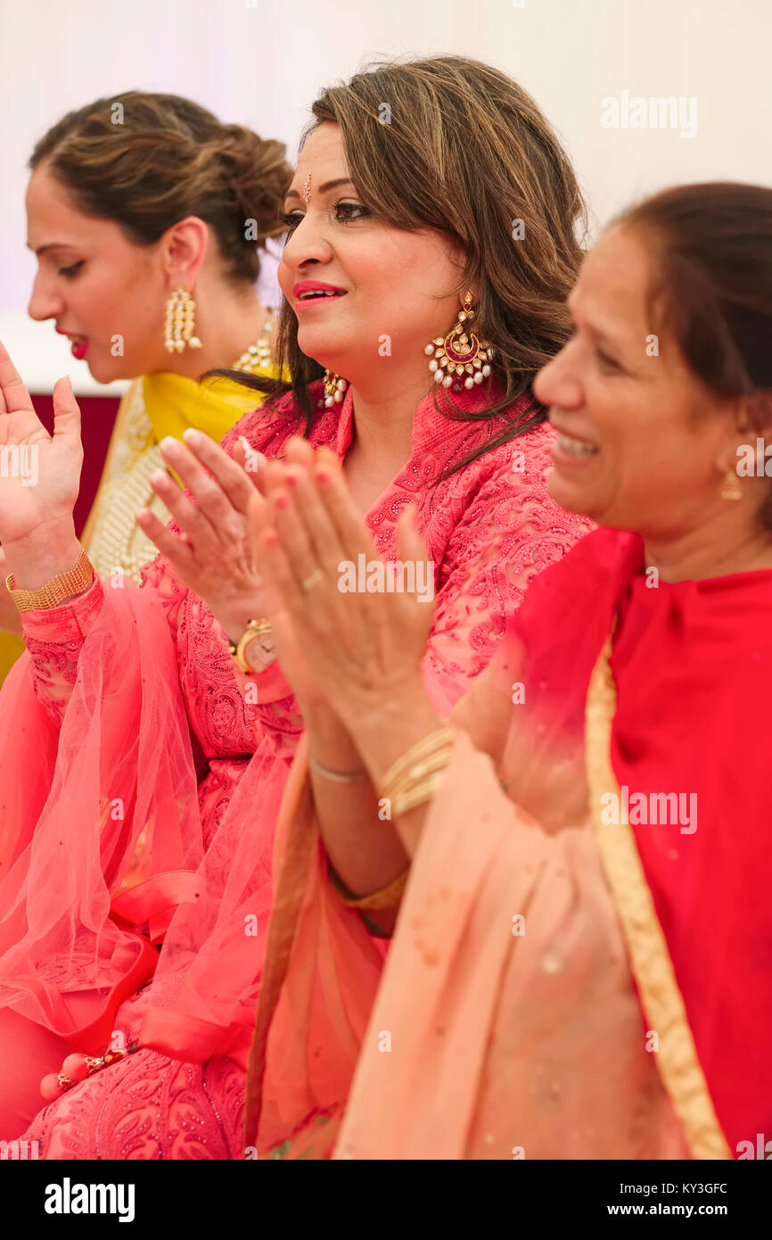 Three Women clapping hands and singing at an Indian Sikh wedding event ...