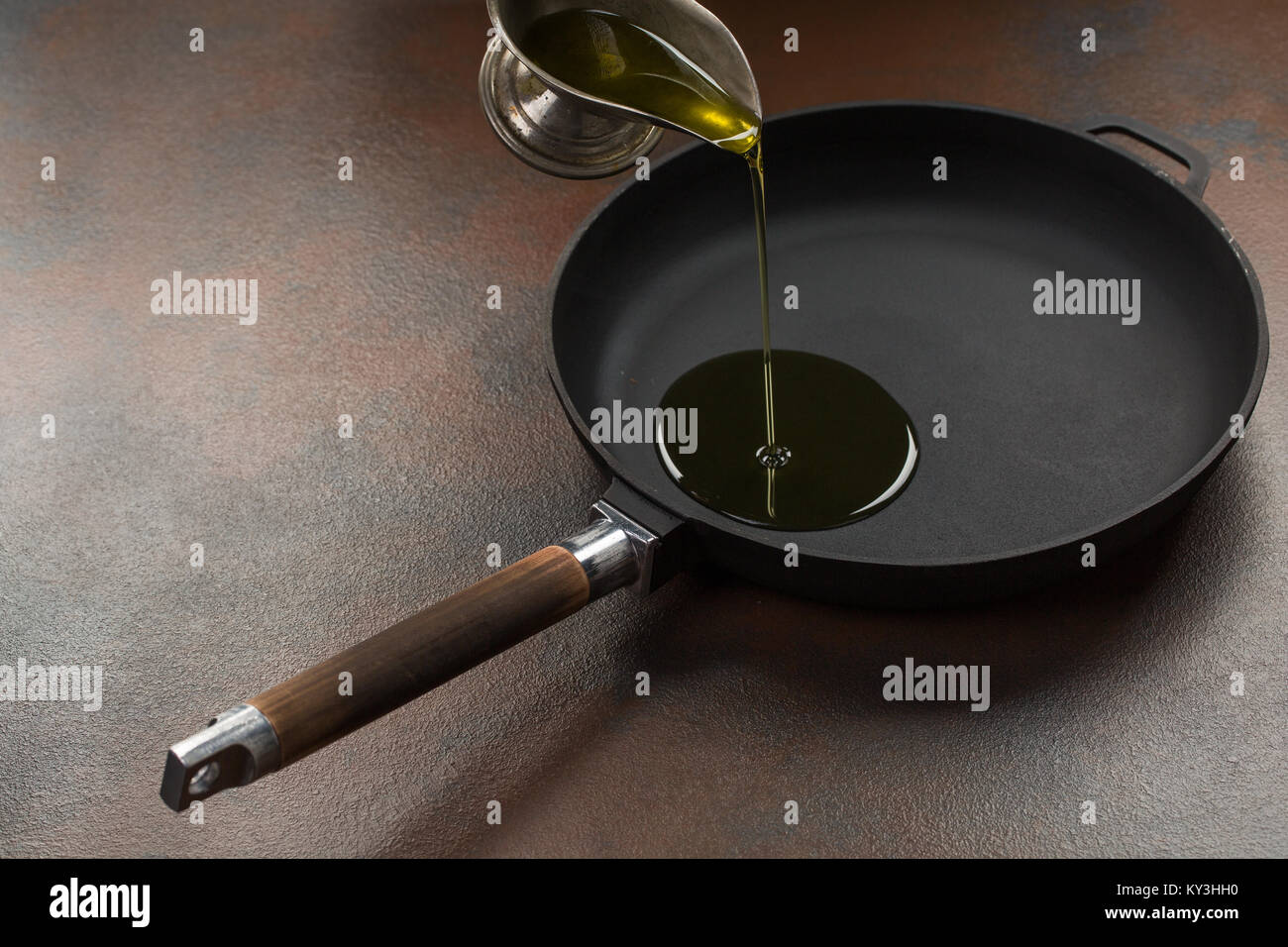 Chef pouring oil in frying pan on dark stone background Stock Photo - Alamy