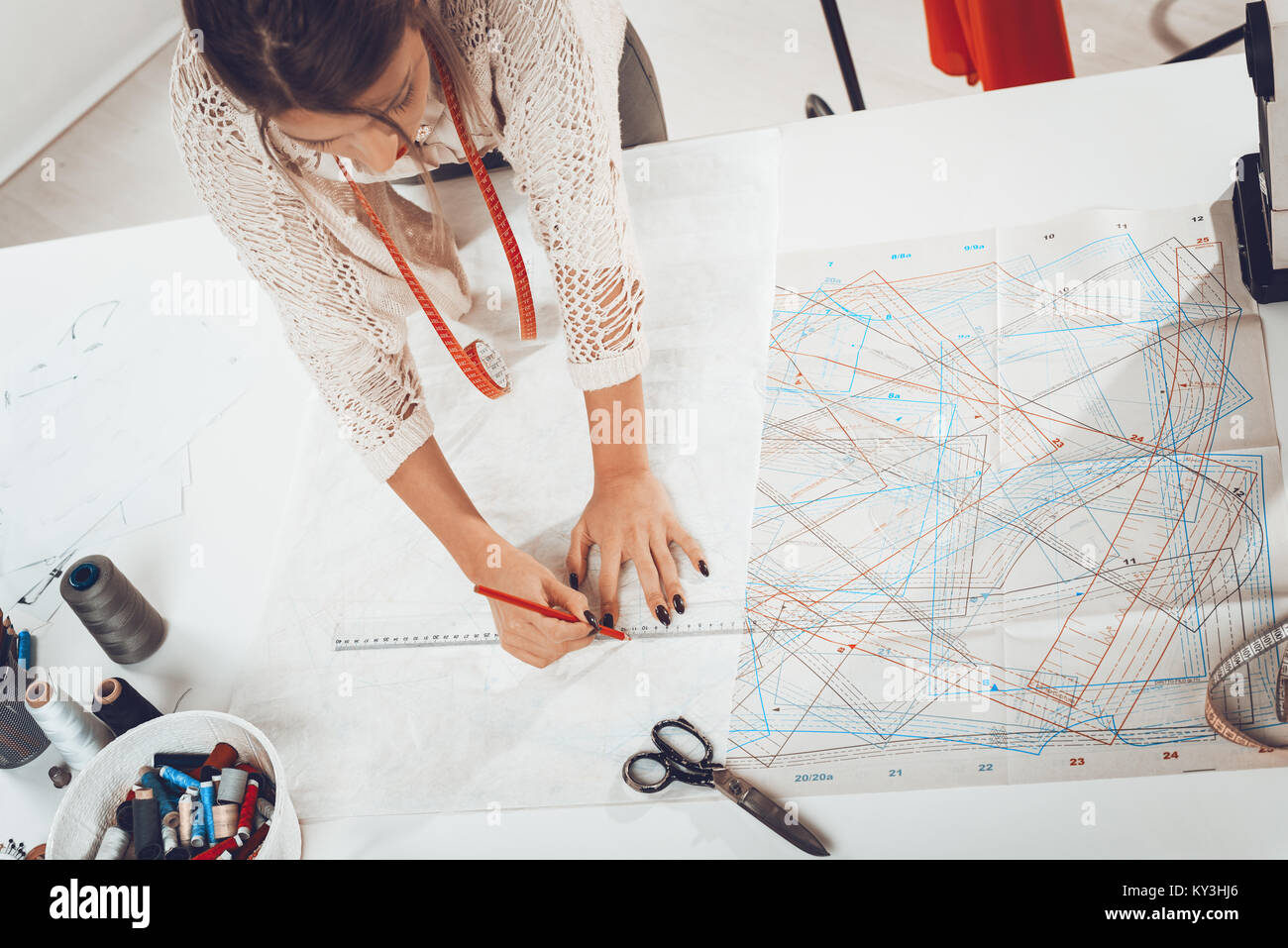 Young female fashion designer with tape measure draped over the neck ...