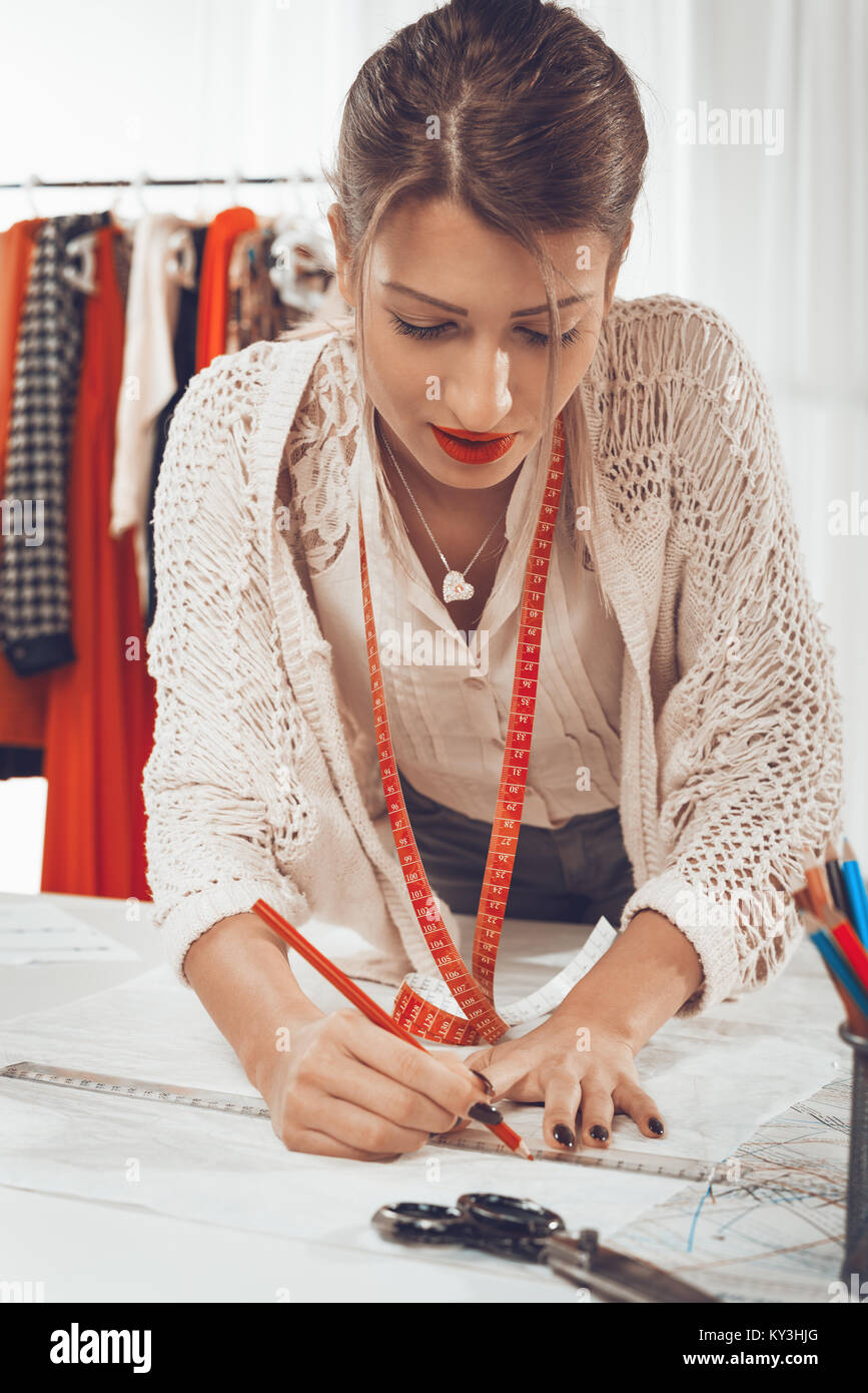 Young female fashion designer with tape measure draped over the neck ...