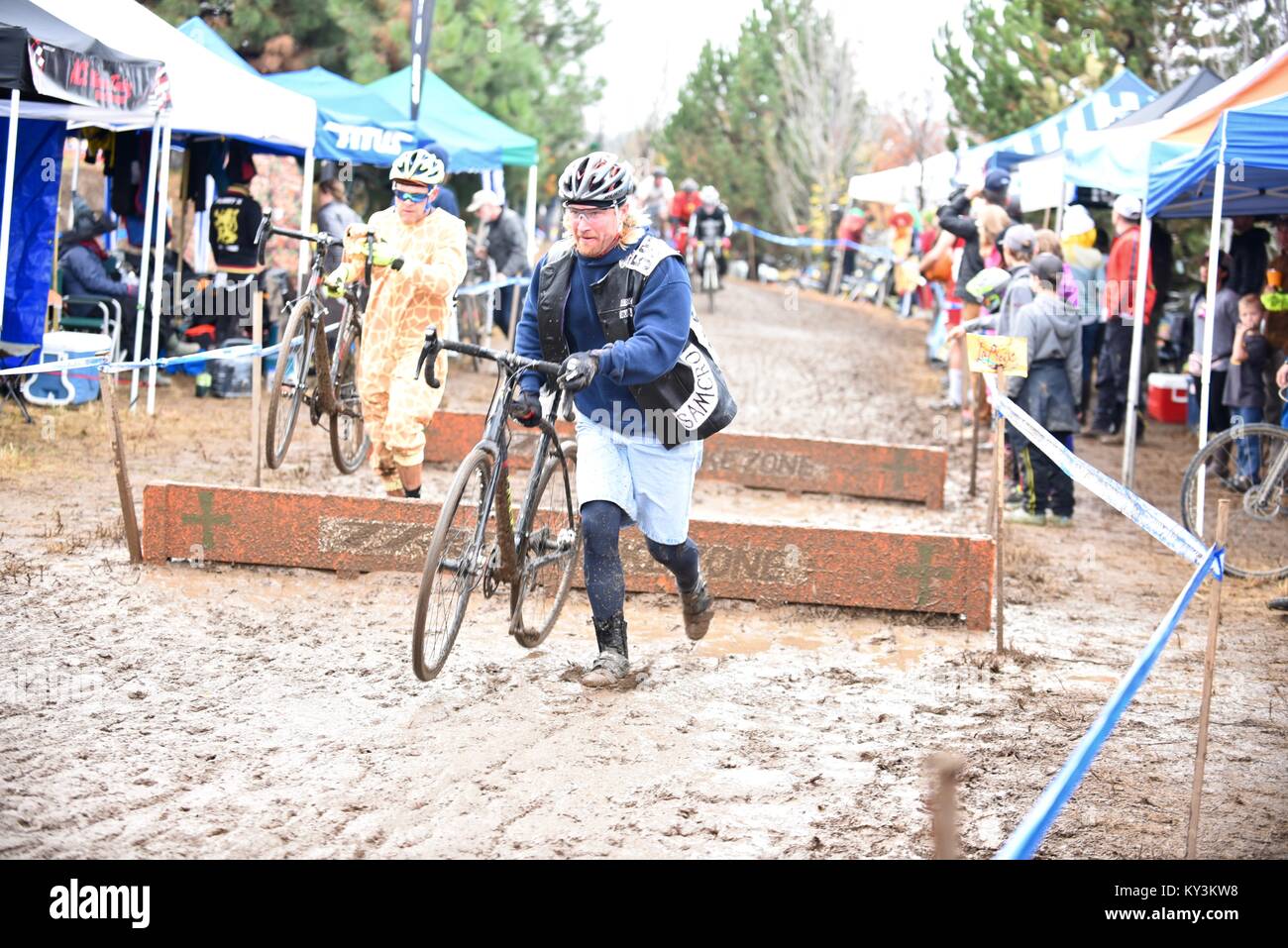 Cyclocross racers traversing diverse terrain, over obstacles, in rainy ...