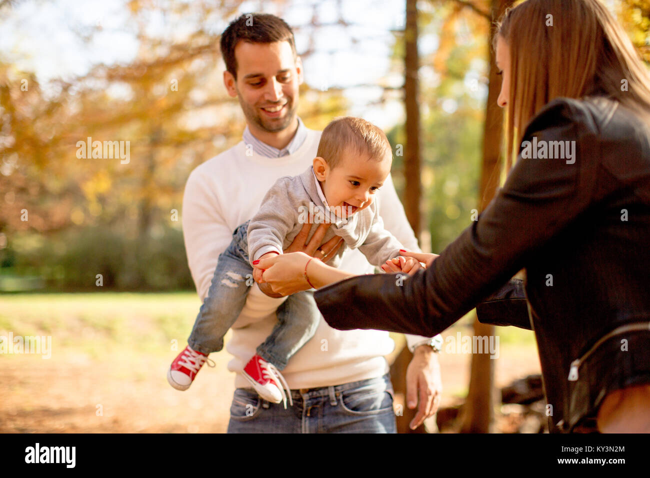 Happy young parents have fun with baby boy in autumn park Stock Photo ...