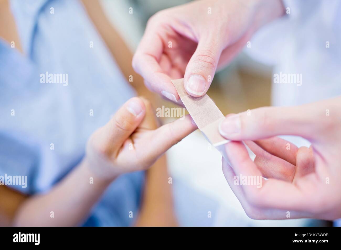 Woman applying plaster to girl's finger Stock Photo - Alamy