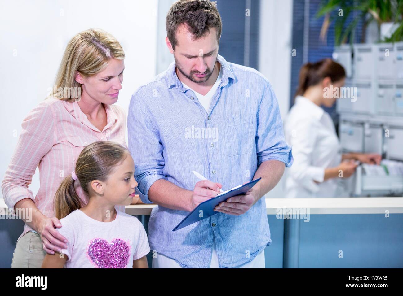Family in medical waiting room, man filling out paperwork Stock Photo ...