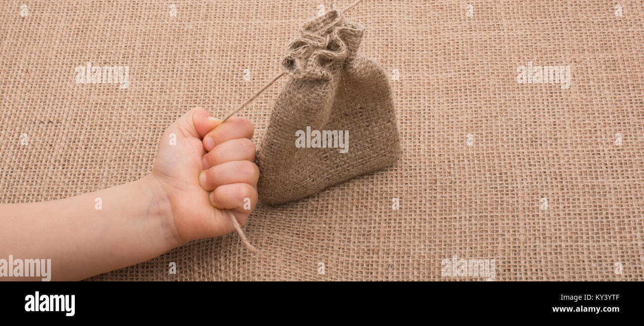 Hand holding an empty little sack made of linen Stock Photo - Alamy