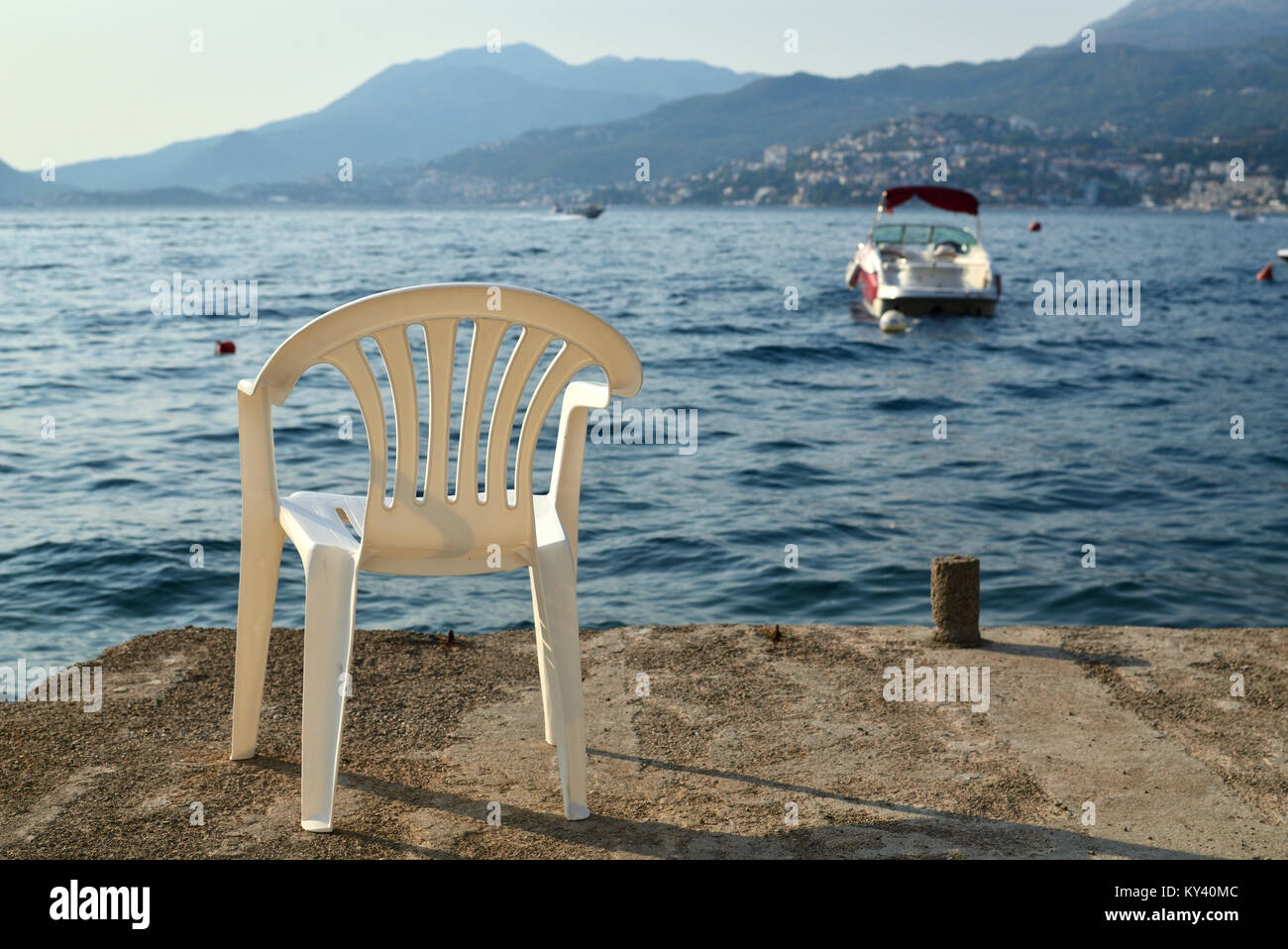 White plastic chair on a beach with a view to a sea and a boat Stock ...