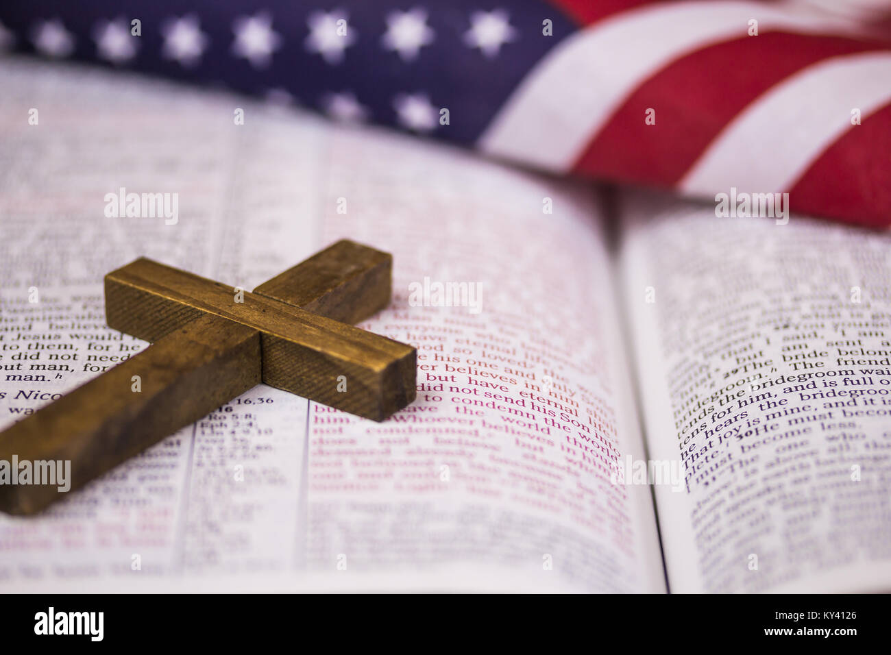 A holy Christian cross laying on an open Bible with an American flag in ...