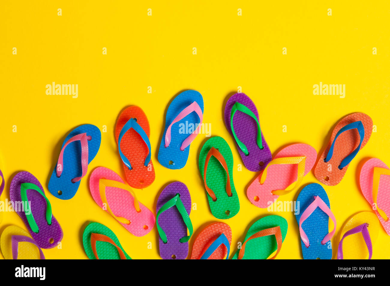 collection of colourful summer flip flop sandals on a bright yellow ...