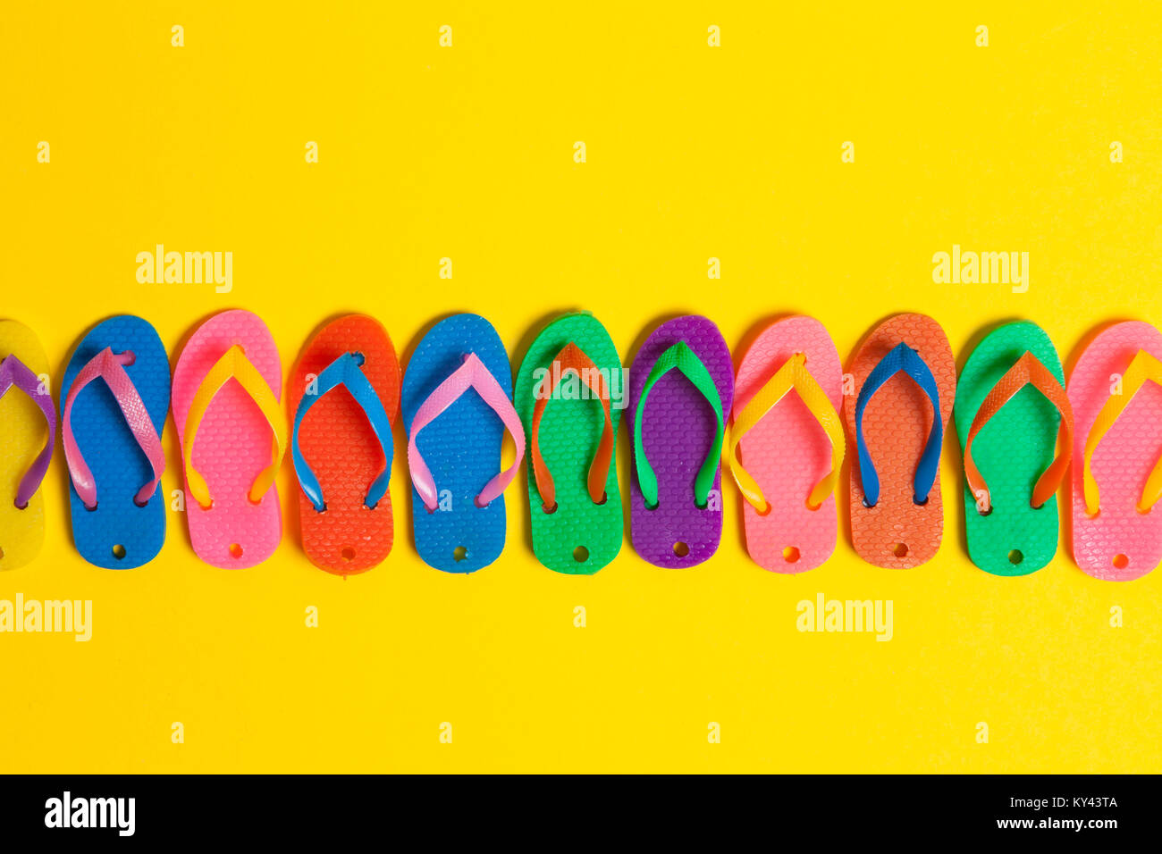 collection of colourful summer flip flop sandals on a bright yellow ...