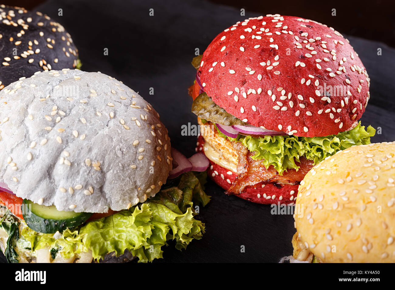 A lot of hamburgers based on different color buns, with vegetables ...