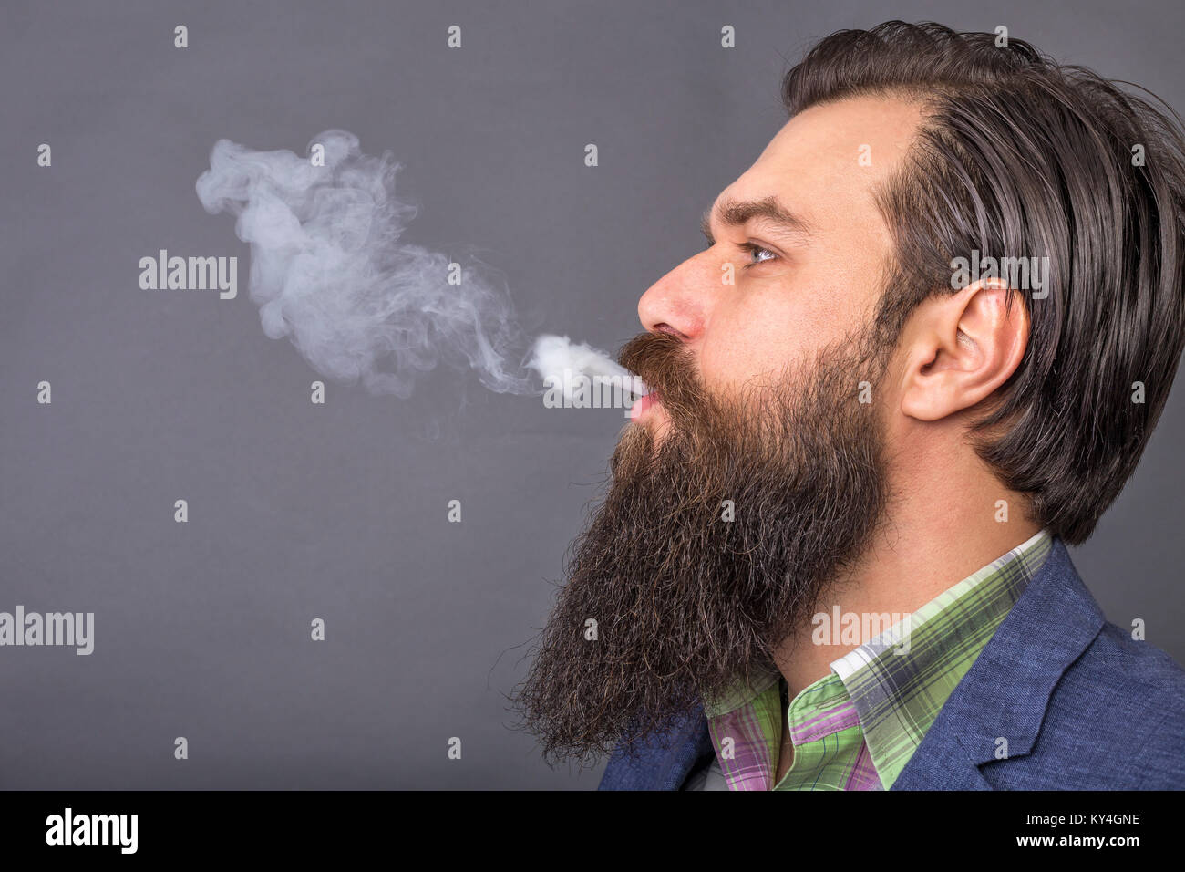 Studio shot of a handsome young man with retro look smoking over gray ...