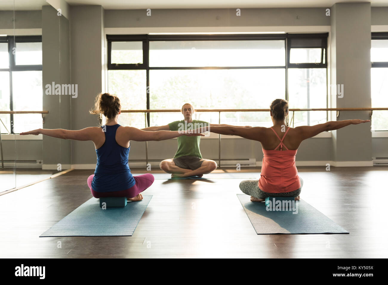 Trainer assisting women in practicing yoga Stock Photo - Alamy