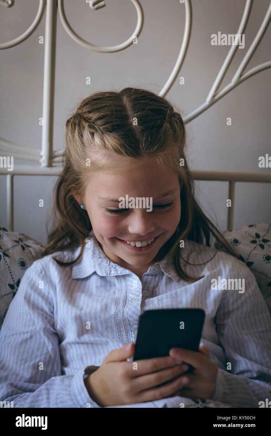 Happy girl using mobile phone on bed Stock Photo - Alamy