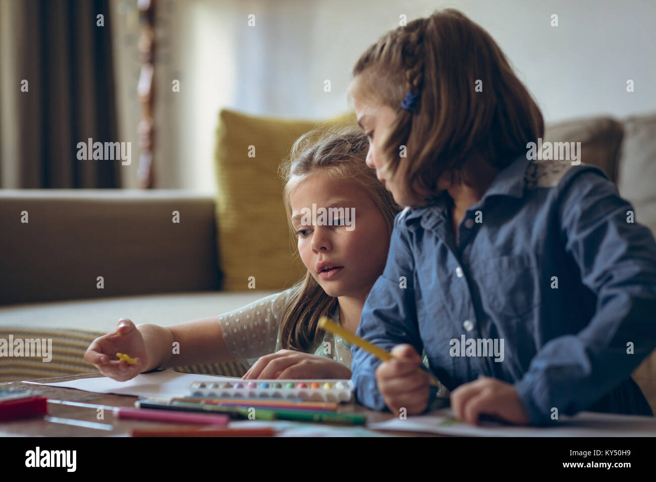 Siblings studying together in living room Stock Photo - Alamy