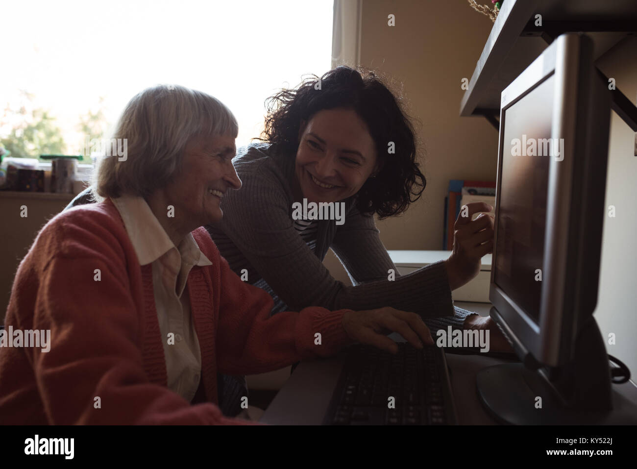 Caretaker assisting senior woman while working on computer Stock Photo ...