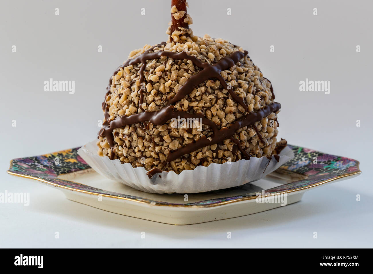 apple coated with chocolate and nuts on a stick on colorful dish Stock ...