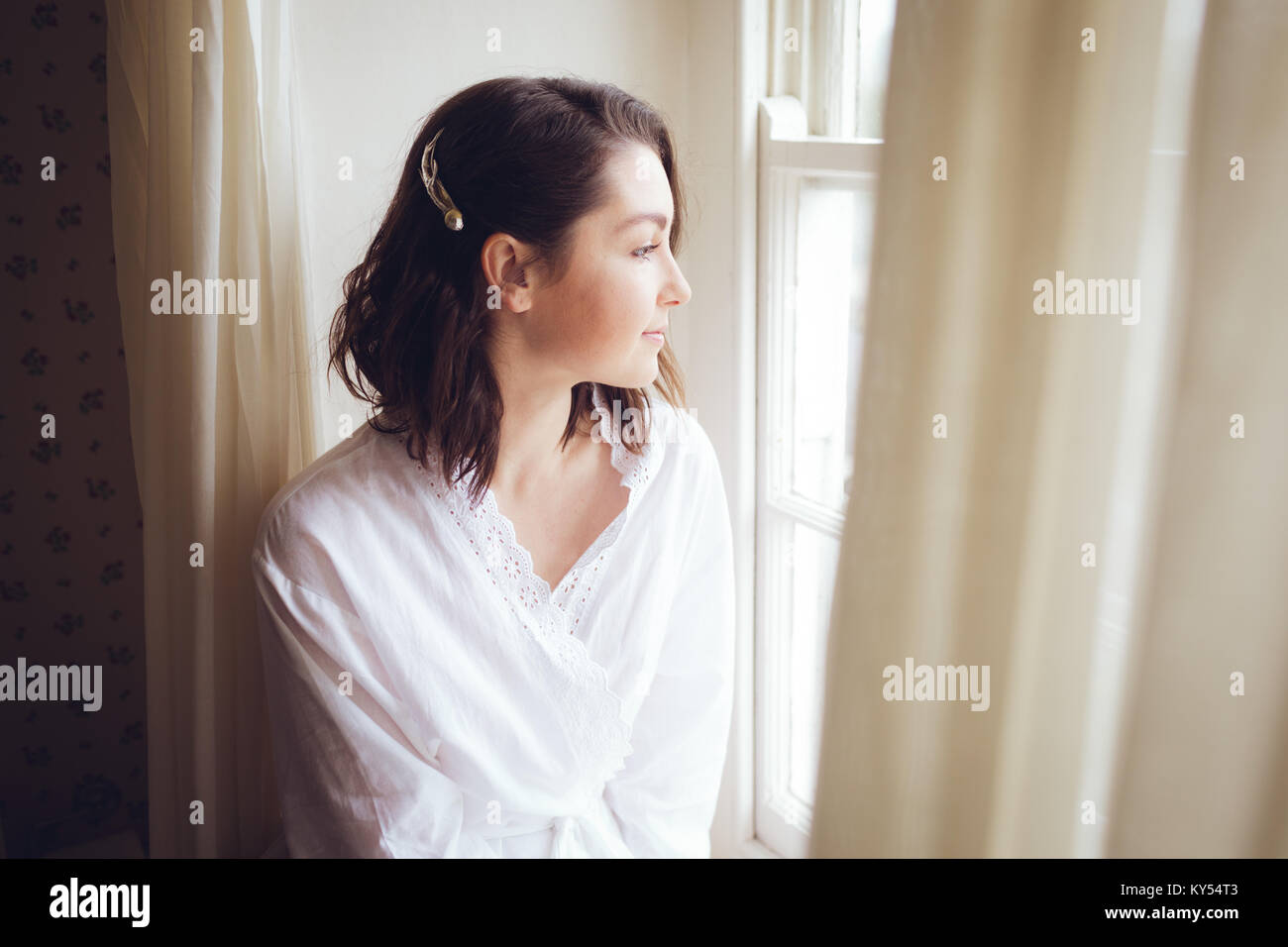 Beautiful woman looking out of the window Stock Photo - Alamy