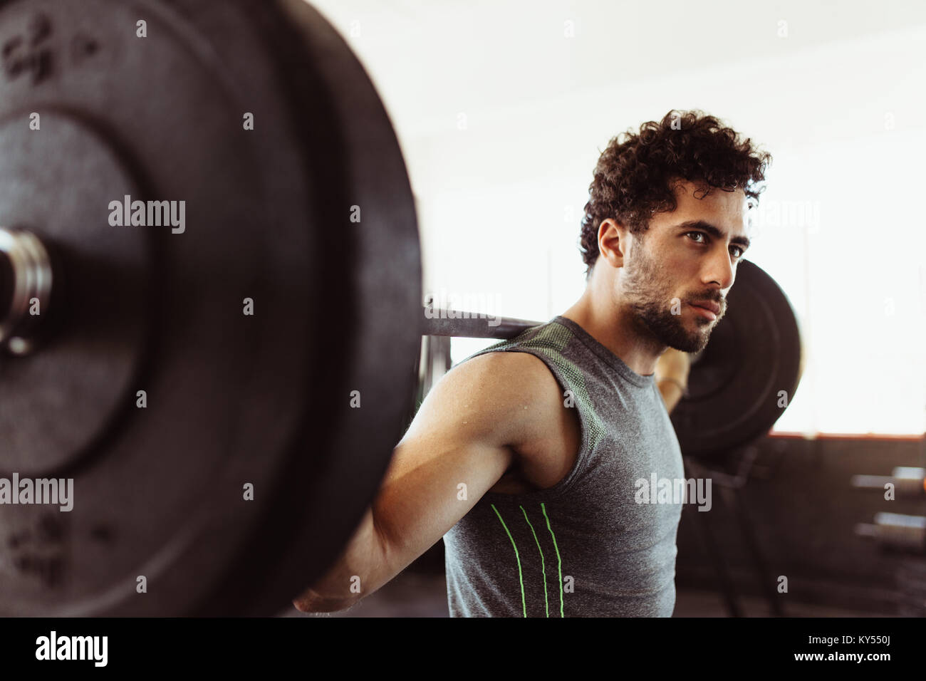 Healthy young guy at gym exercising with barbell. Fit young man working ...