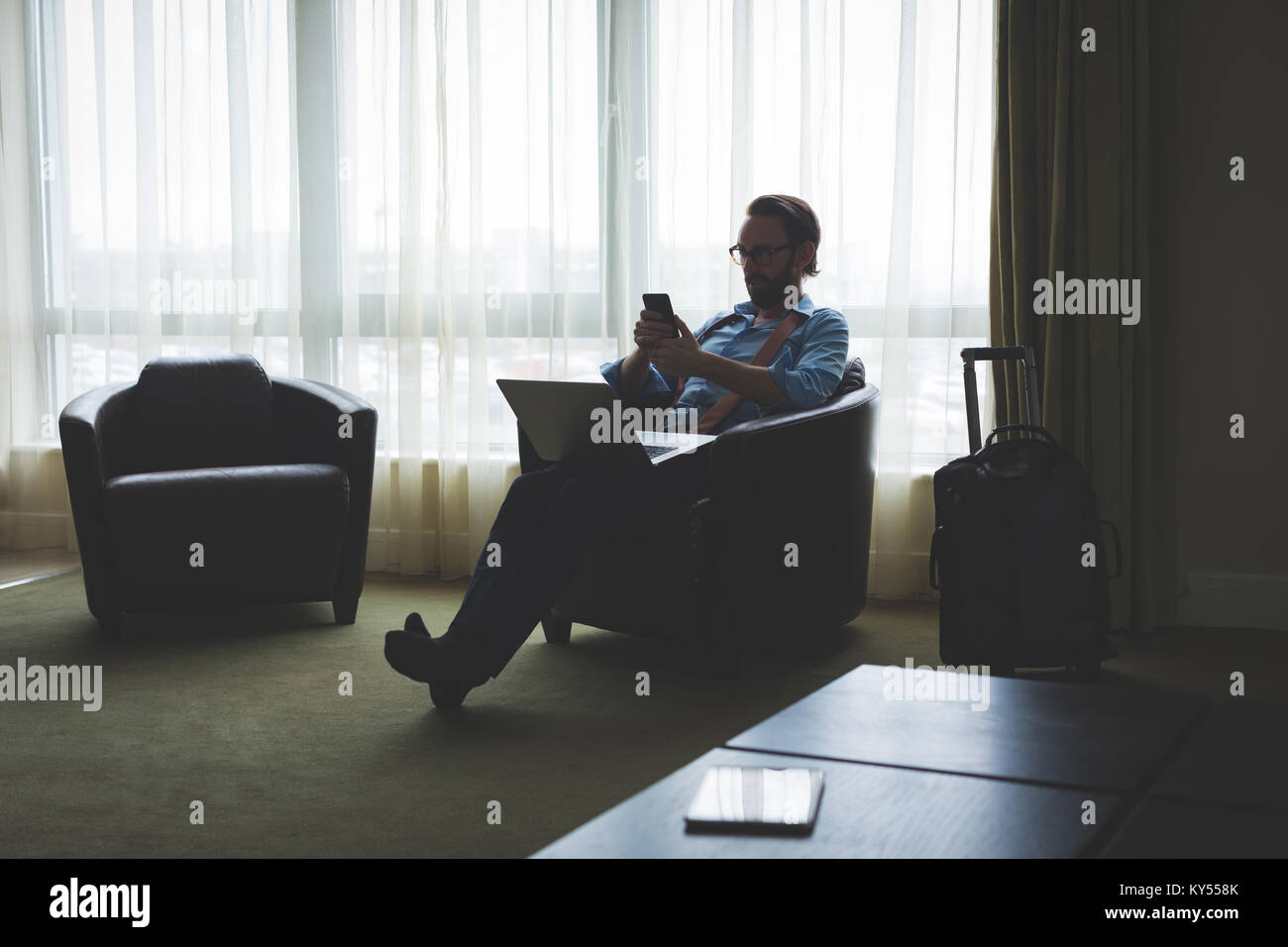 Businessman using mobile phone while sitting on arm chair Stock Photo ...