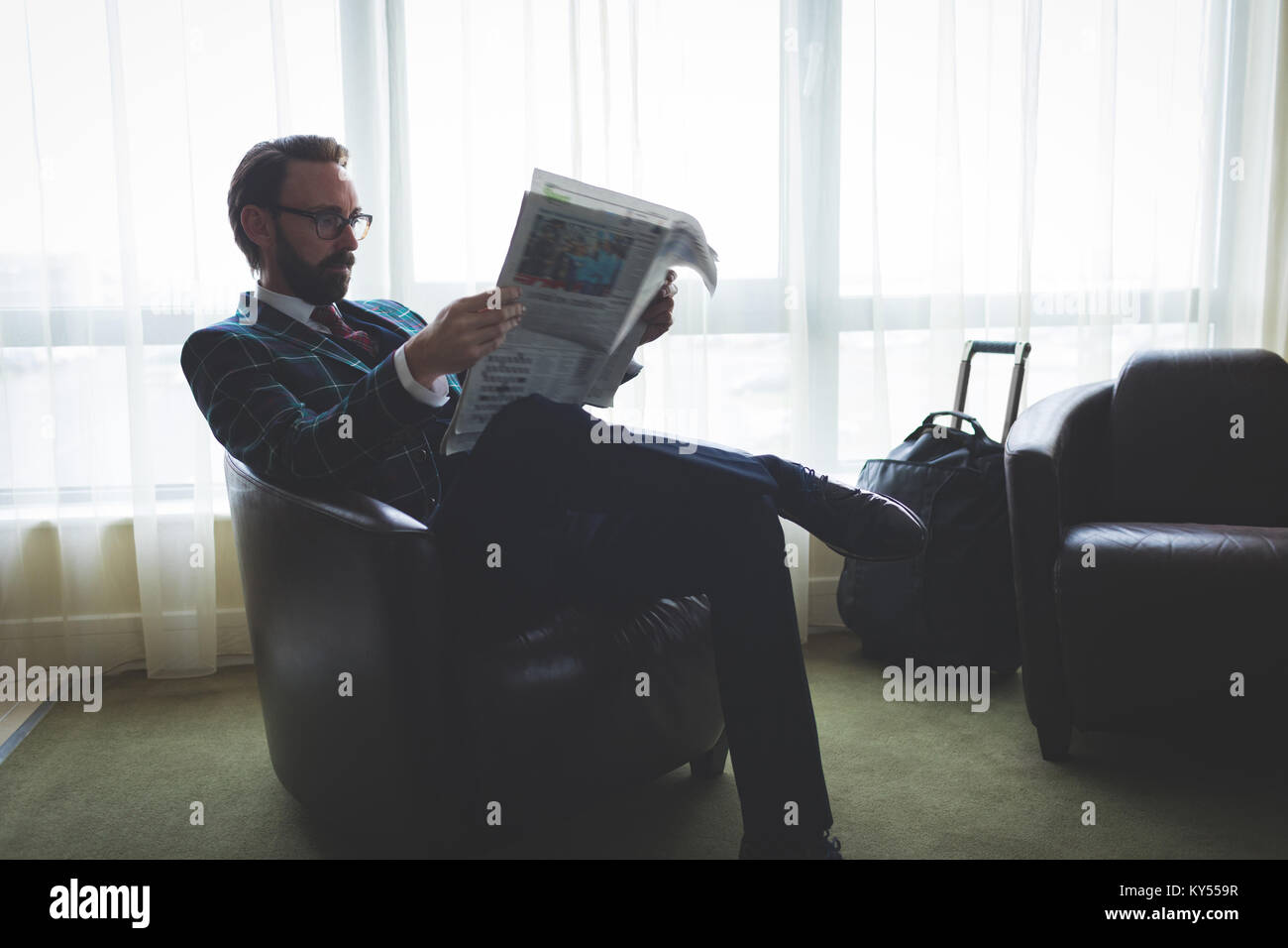 Businessman reading newspaper on arm chair Stock Photo - Alamy
