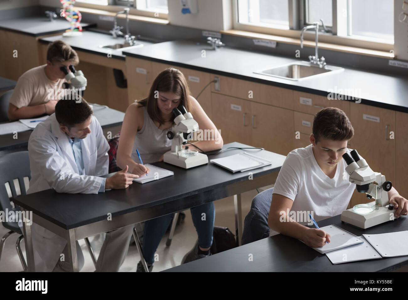 Teacher assisting students in experiment Stock Photo - Alamy