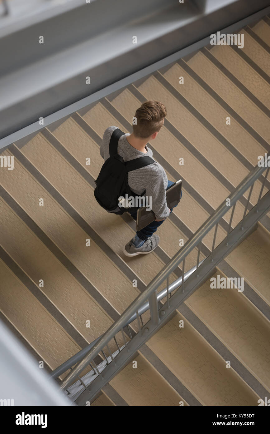 College student walking with laptop on staircase Stock Photo - Alamy