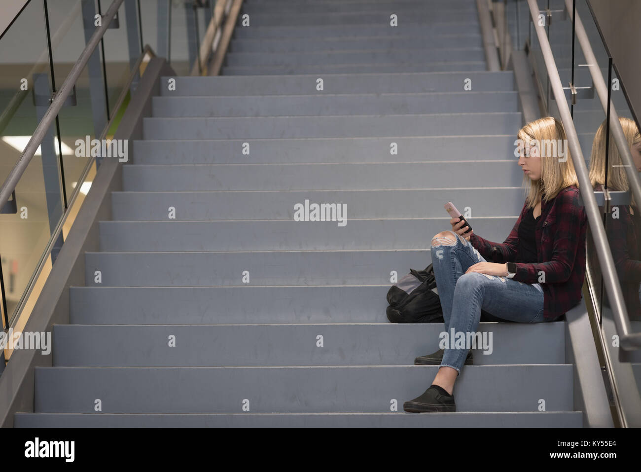 Teenage girl using mobile phone on staircase Stock Photo - Alamy