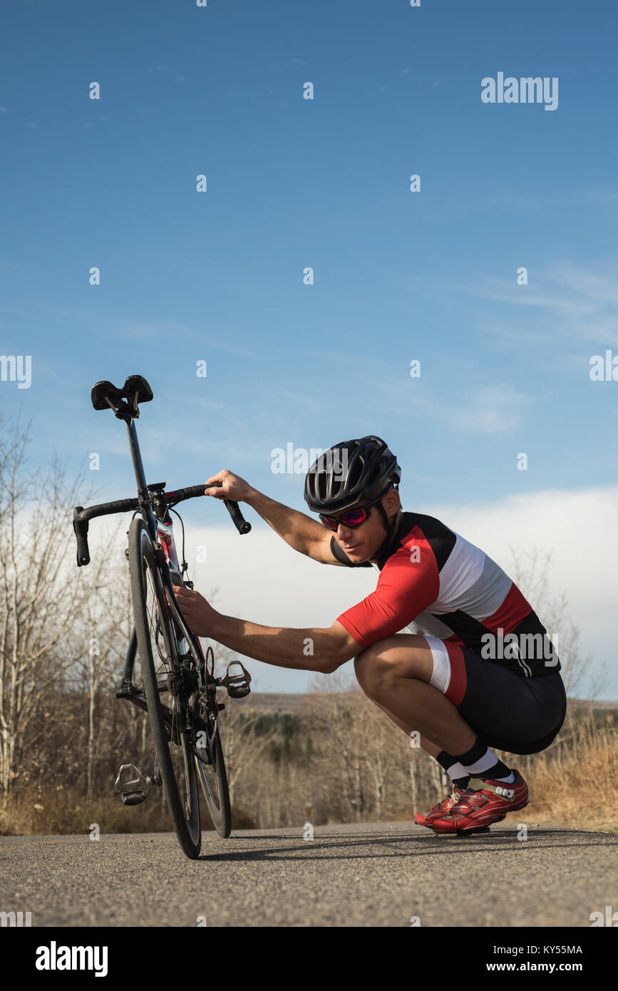 Biker checking his mountain bike on road Stock Photo - Alamy